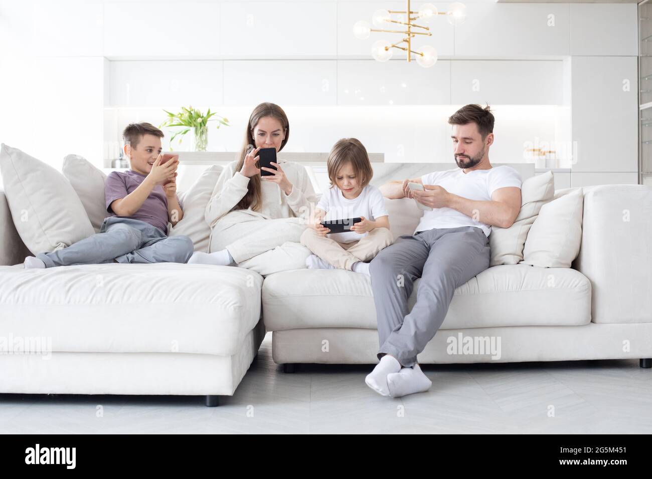 Caucasian parents and kids use devices together sit on sofa, tech ...