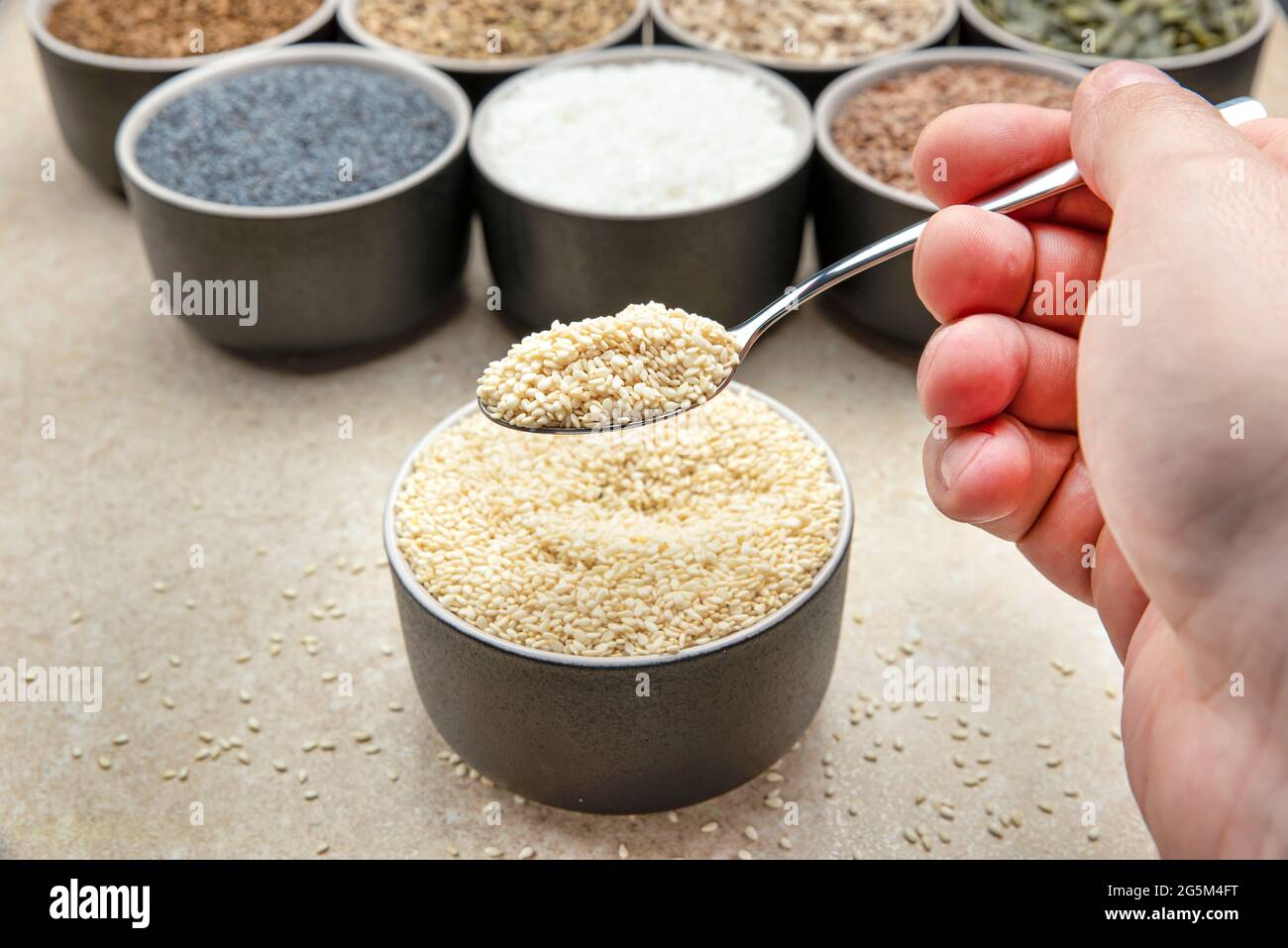 White sesame seeds, sesame seeds in a black saucer on a background of ...