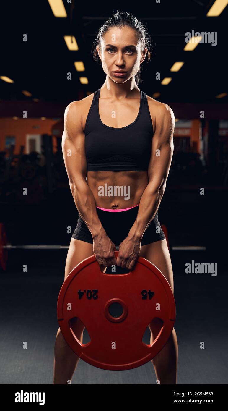 Strong female bodybuilder exercising with round weight plates Stock ...