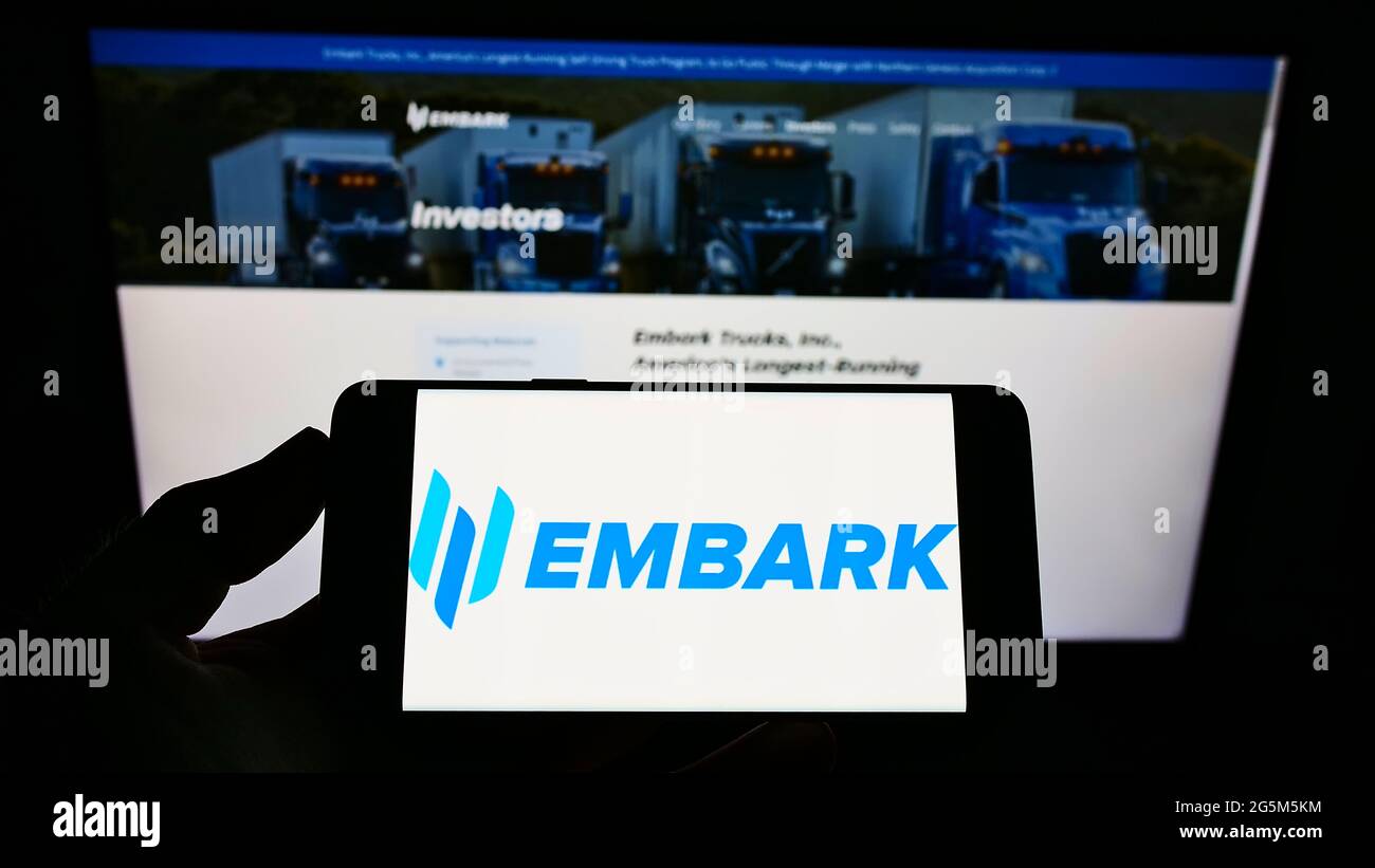 Person holding mobile phone with logo of US autonomous driving company ...