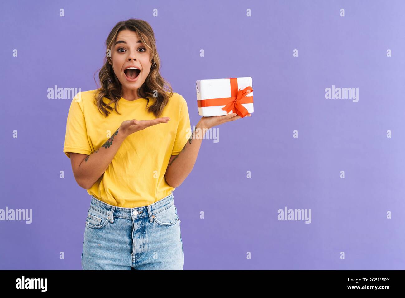 Happy excited young woman showing present box isolated over blue ...