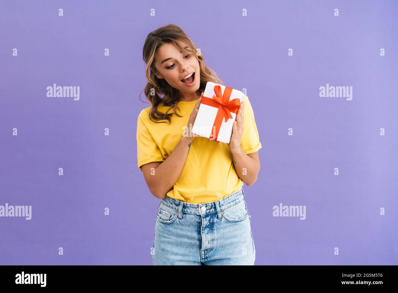 Happy excited young woman showing present box isolated over blue ...