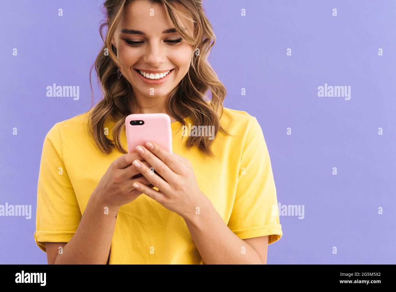 Happy beautiful girl smiling while using mobile phone isolated over ...