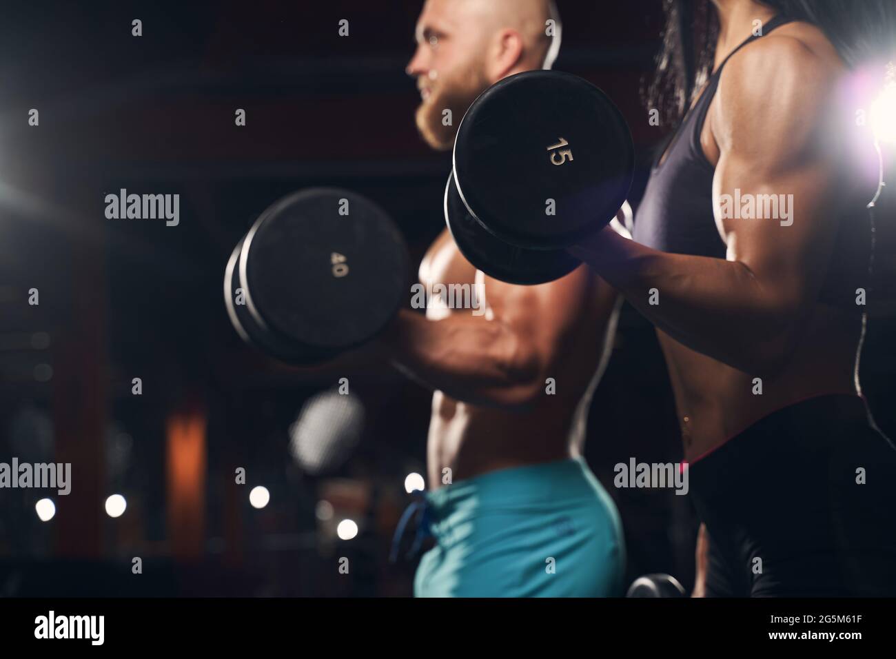 Strong man and muscled woman lifting weights at the gym Stock Photo - Alamy