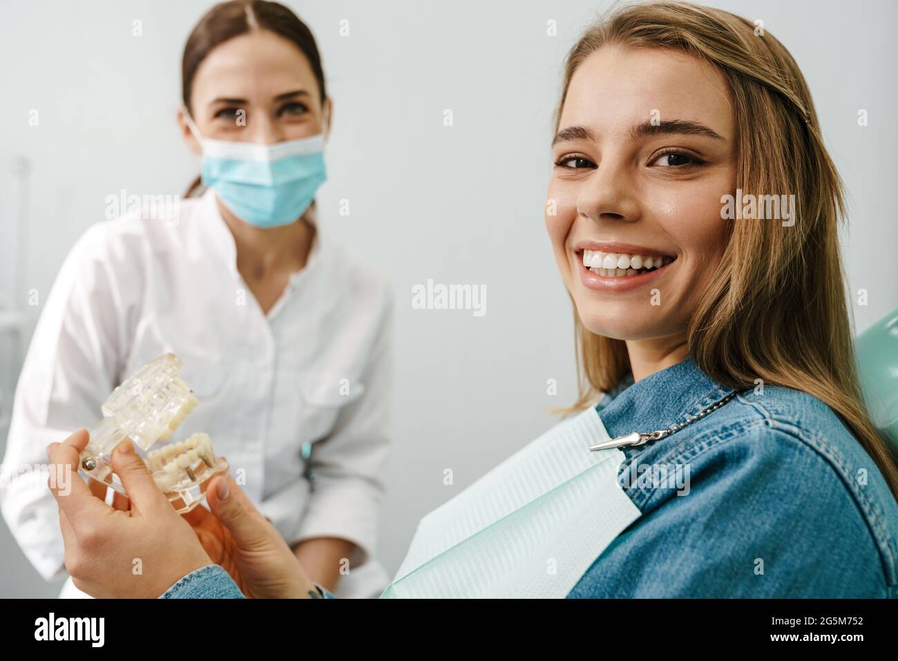 European mid happy dentist woman showing teeth imitation to her patient ...