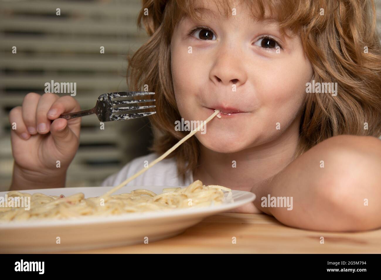 Portrait of a cute child boy eating pasta, spaghetti. Close up ...