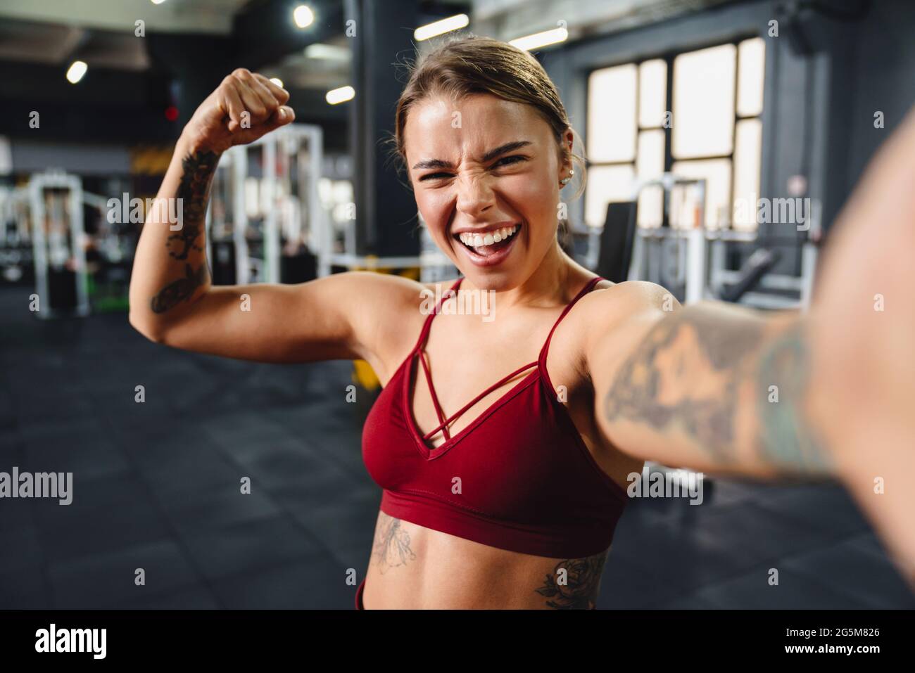 Excited athletic sportswoman showing her bicep and laughing while ...