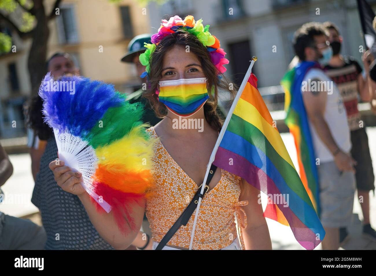 A protester seen holding a flag and a fan with rainbow colors as she ...