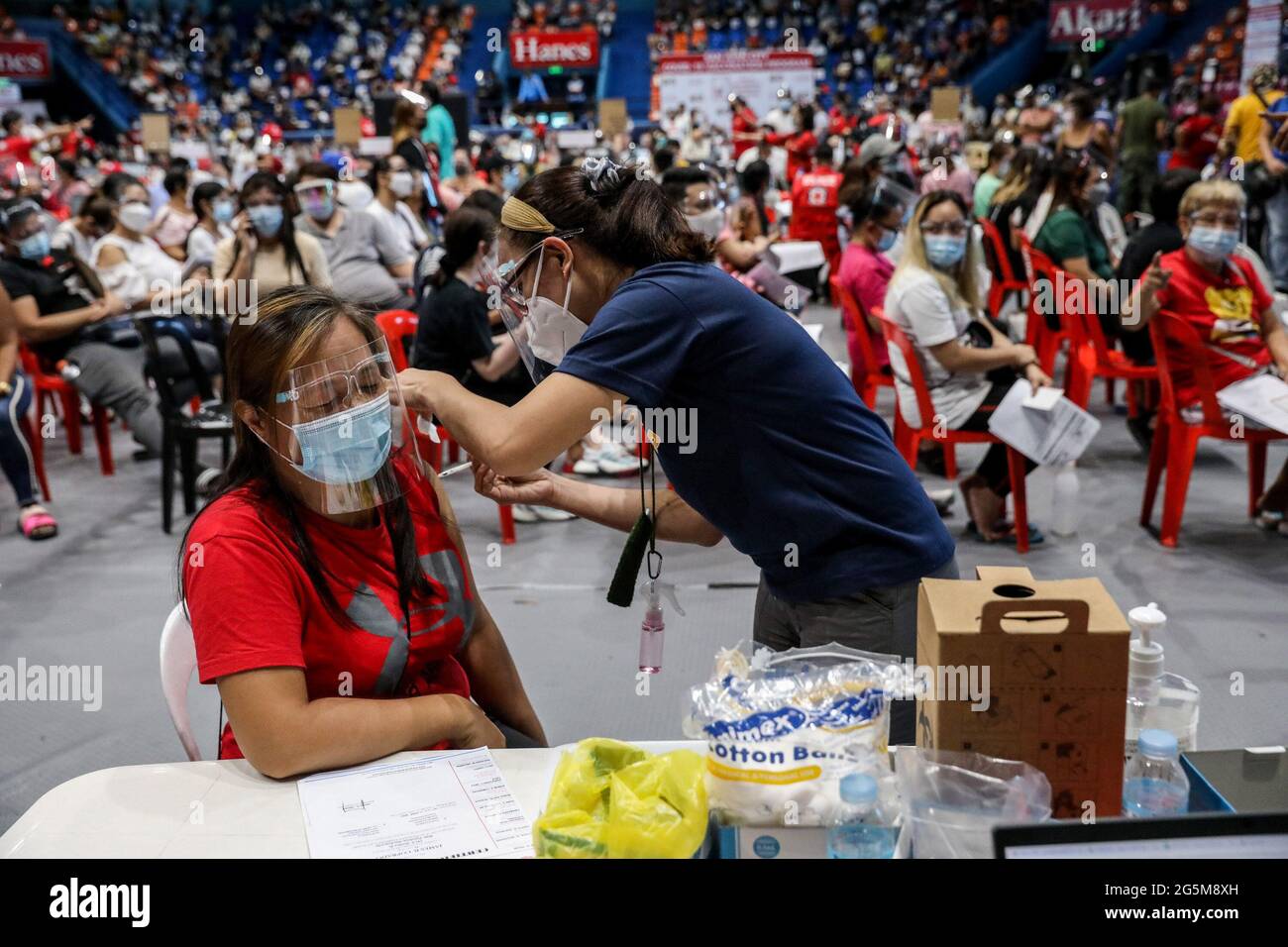 A health worker inoculates a patient with the COVID-19 Pfizer-BioNTech ...