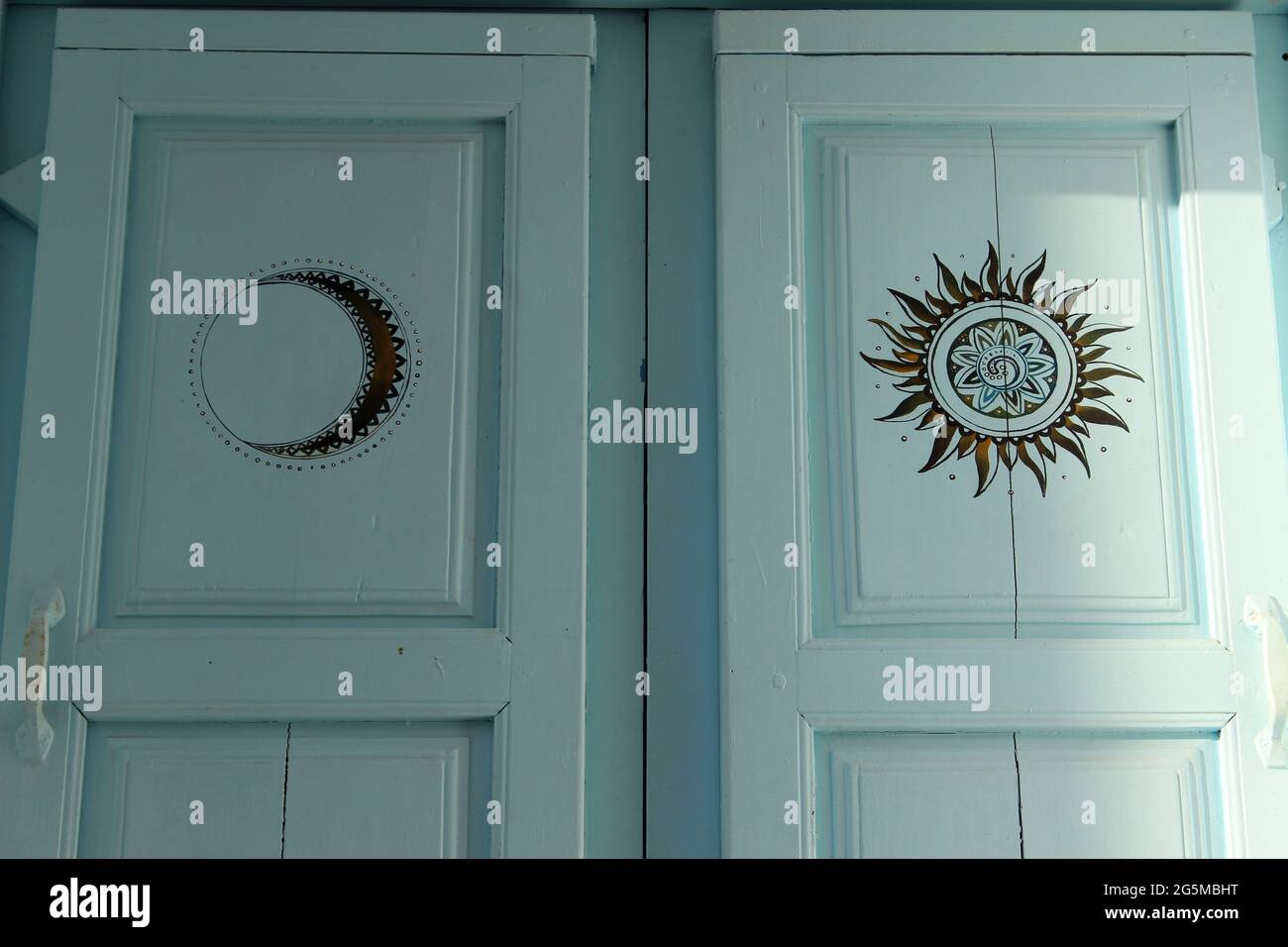 Painted blue doors with sun and moon decals Stock Photo - Alamy