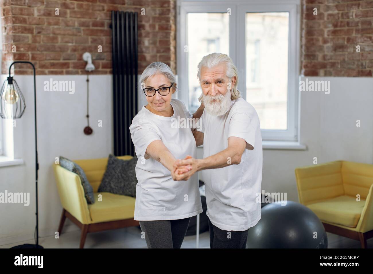 Energetic retired couple in casual clothes moving actively at bright ...