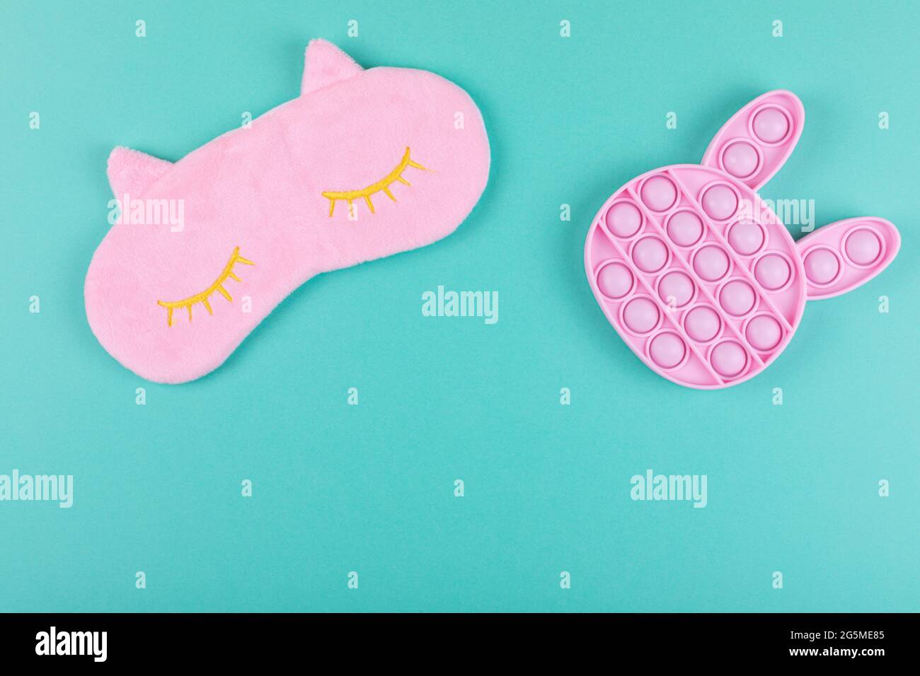 Pink sleep mask and trendy pop it fidget toy on the mint background ...