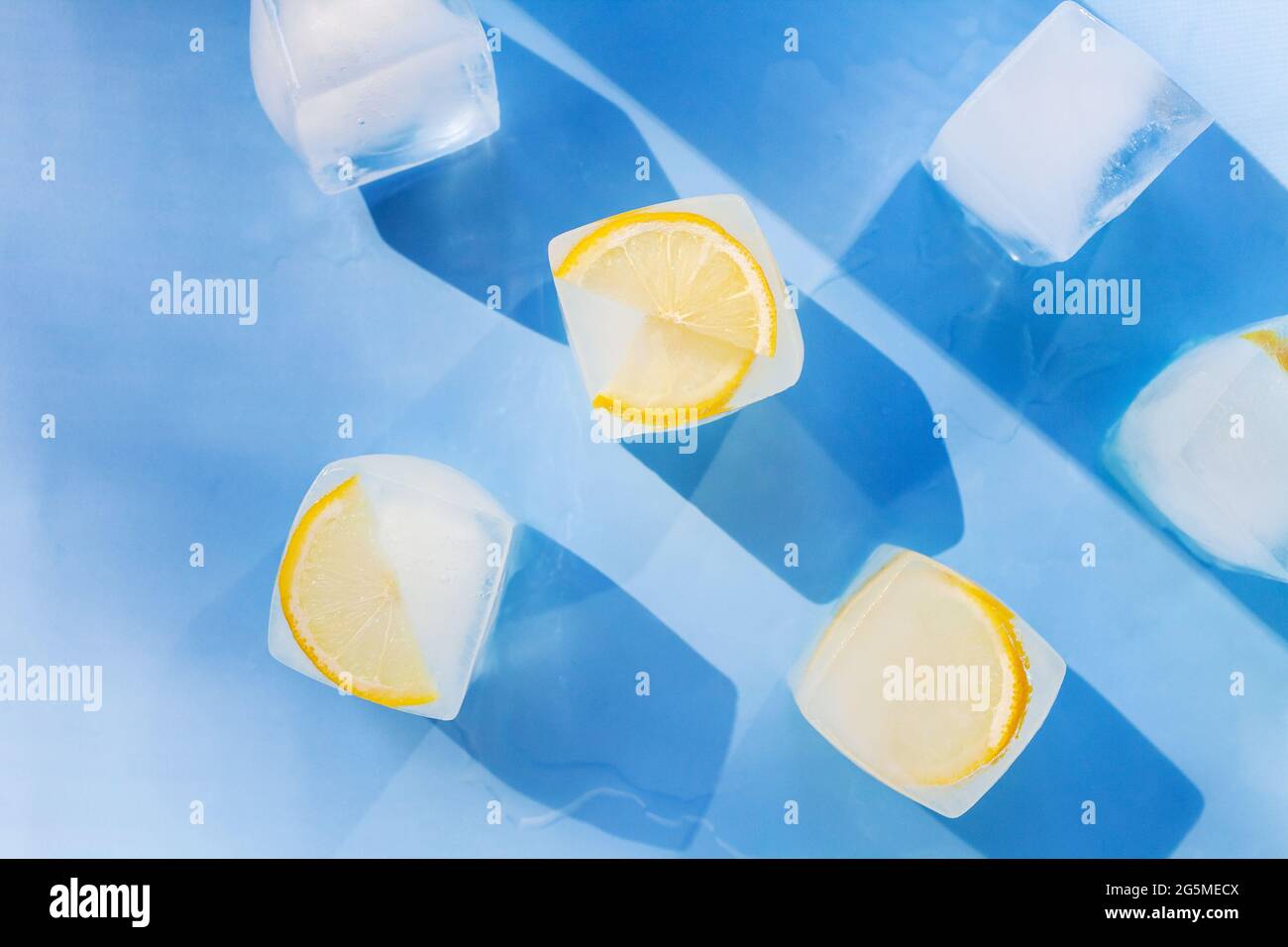 Modern composition of the frozen slices of lemon and ice cubes on a blue background Stock Photo ...