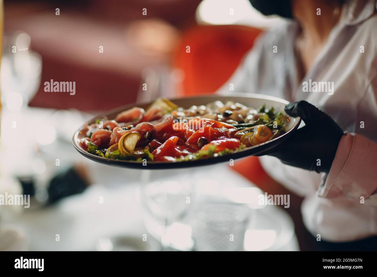 Various cold cuts on a plate waiter catering holds Stock Photo - Alamy