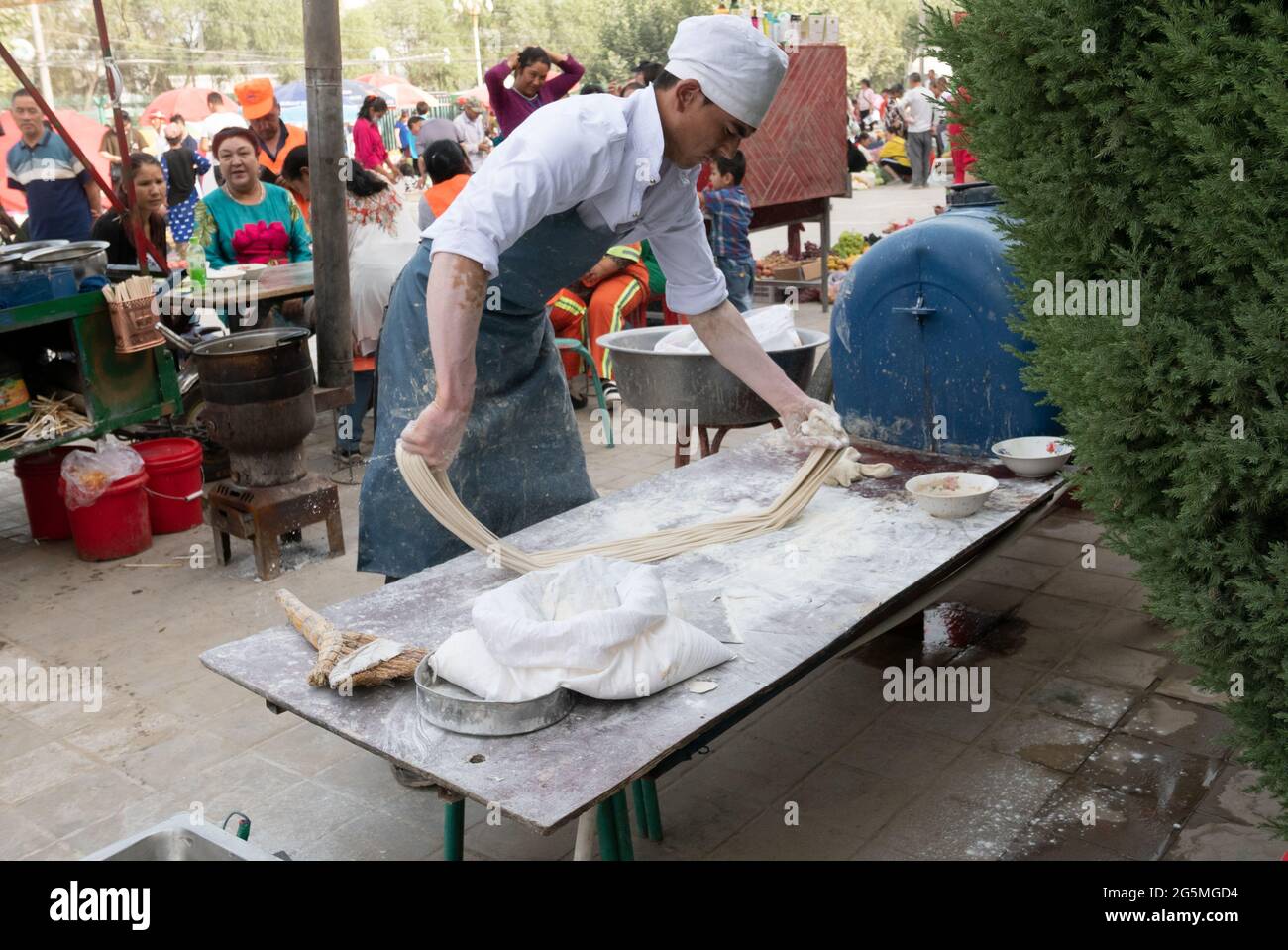 Pulling and folding a strand of dough on the market in Hotan Stock ...