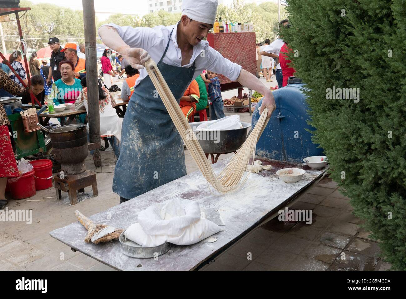 Pulling and folding a strand of dough on the market in Hotan Stock ...