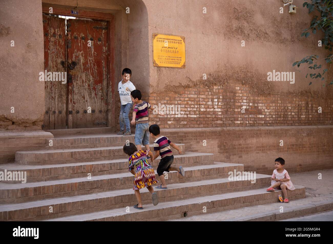 Five children are playing on a staircase leading to an old weathered ...