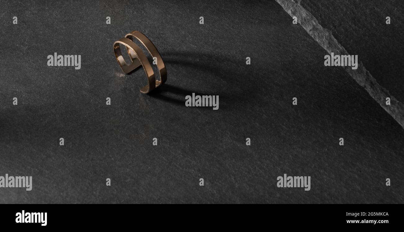 Double shape modern golden ring on dark stone surface Stock Photo - Alamy