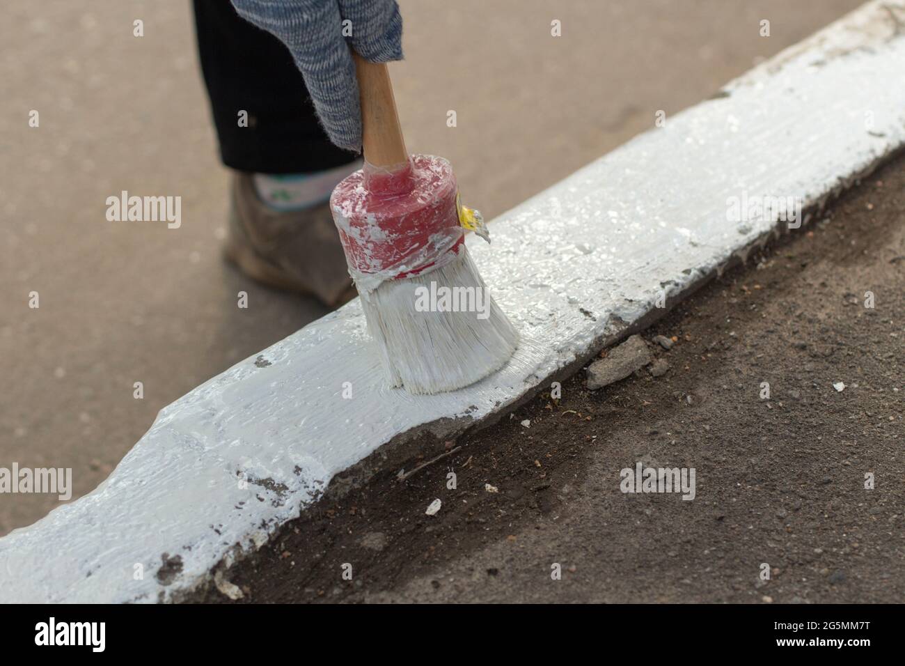 Painting borders with white paint. Applying oil paint to asphalt ...