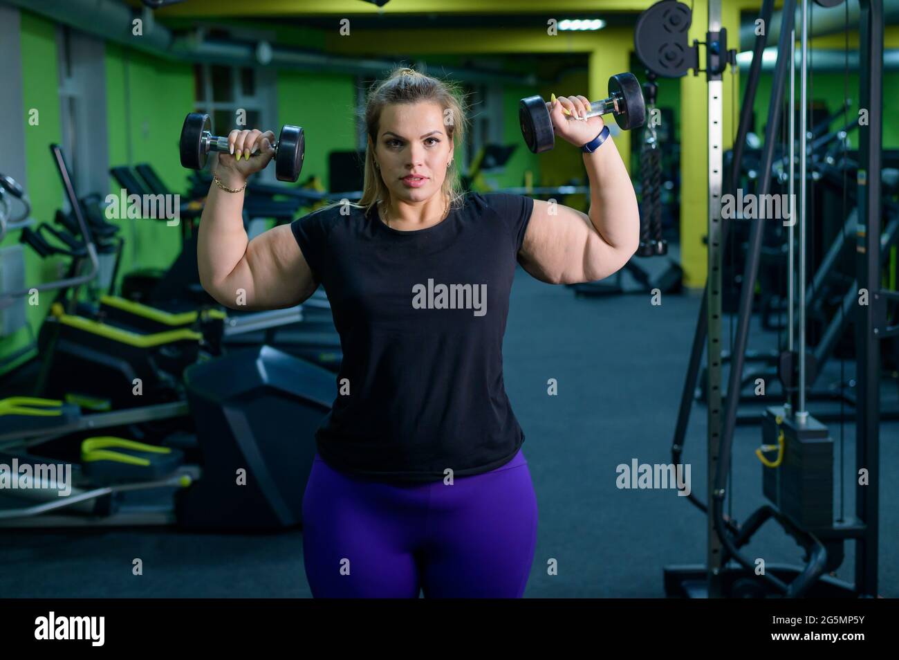 An obese woman is working on losing weight. Fat blondes train biceps ...