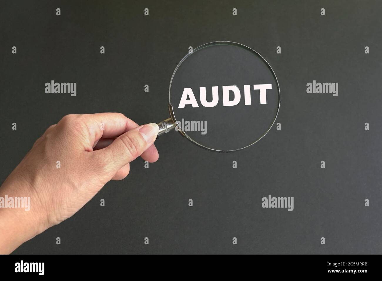 Audit, word on magnifying glass held by hand. Black background Stock ...