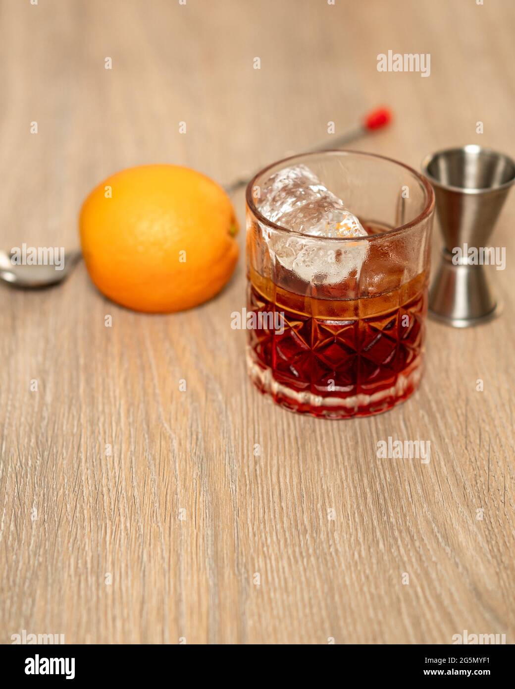 Front view of the preparation of a negroni with mixing spoon and jigger ...