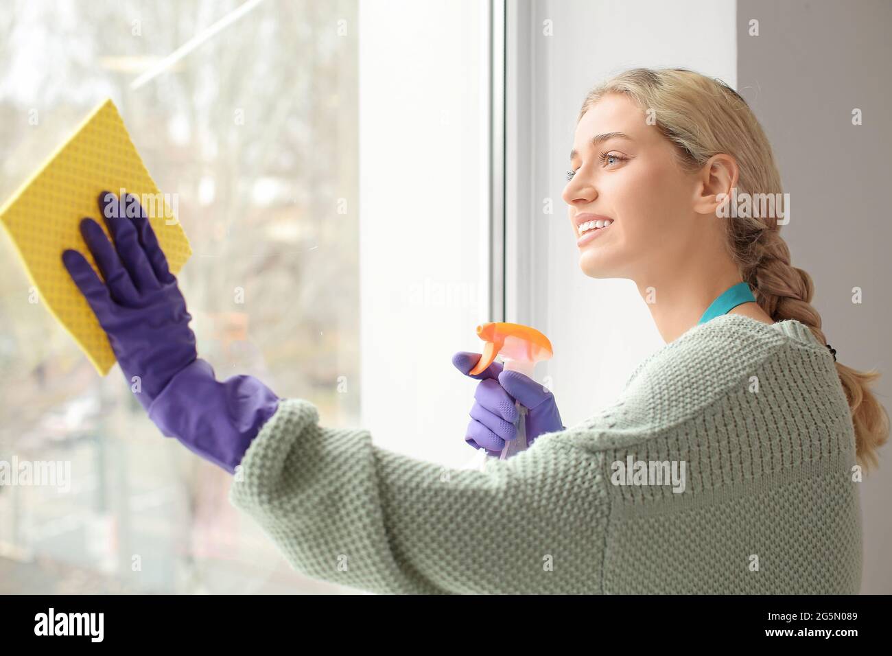 Young woman washing window in her flat Stock Photo - Alamy