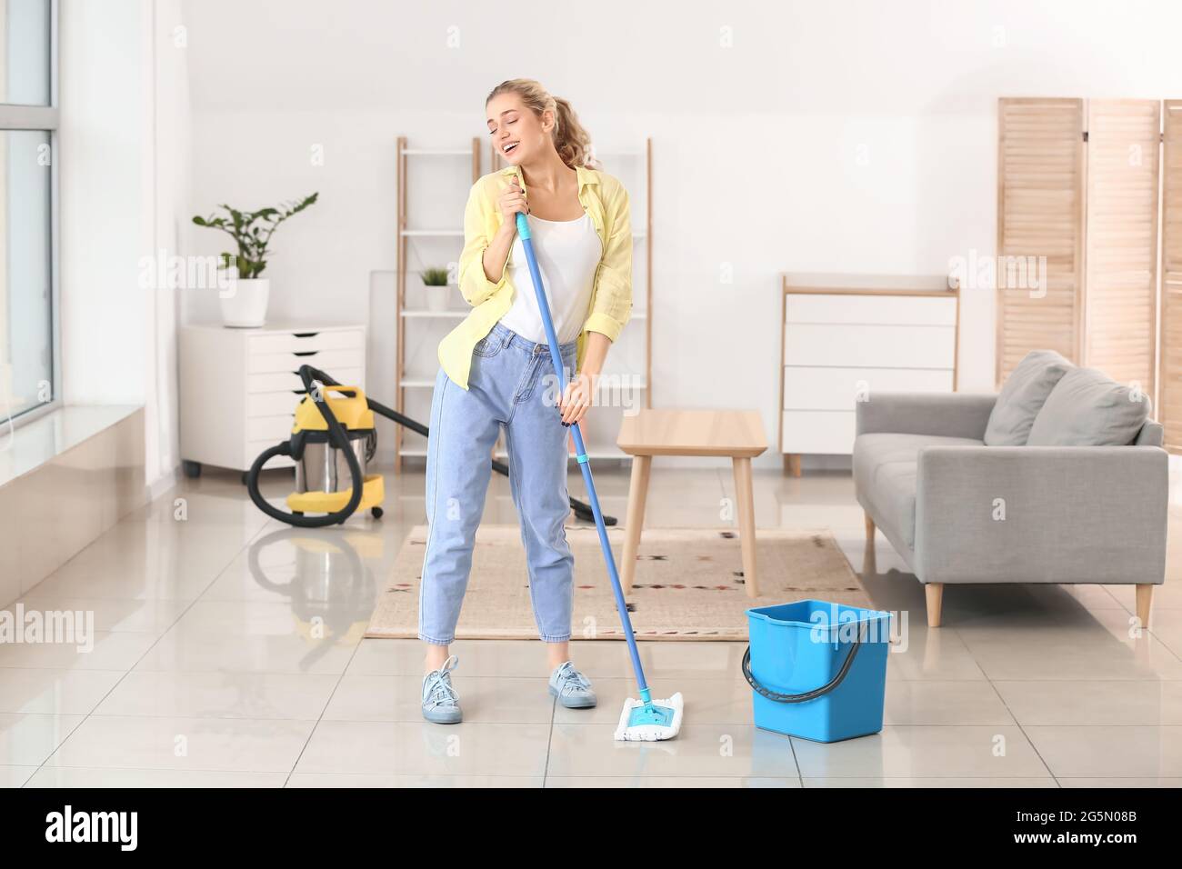 Young woman having fun while mopping floor in her flat Stock Photo - Alamy