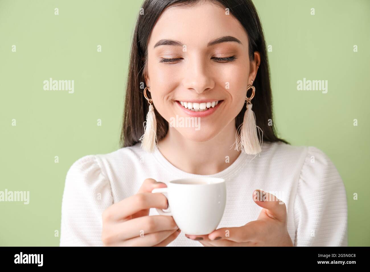 Beautiful young woman with cup of coffee on color background, closeup ...