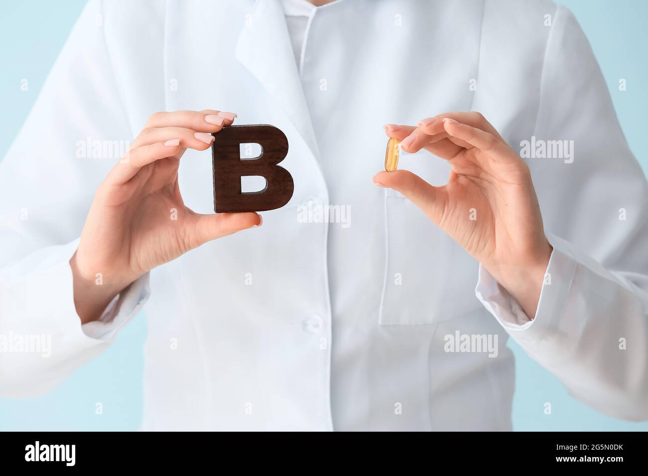 Female doctor holding letter B and pill on color background, closeup ...