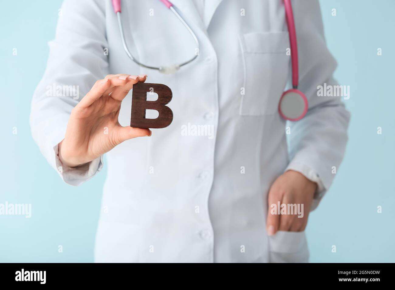 Female doctor with letter B and stethoscope on color background ...