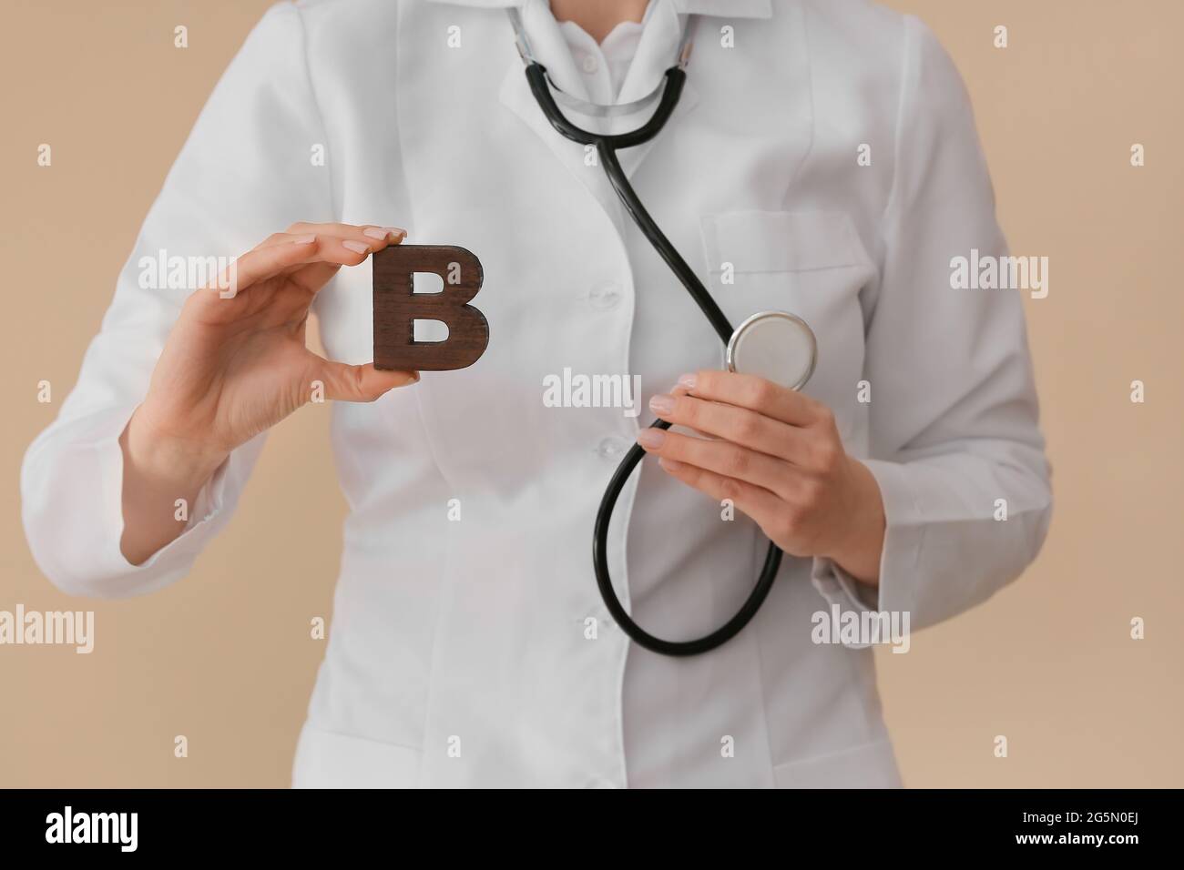 Female doctor with letter B and stethoscope on color background ...