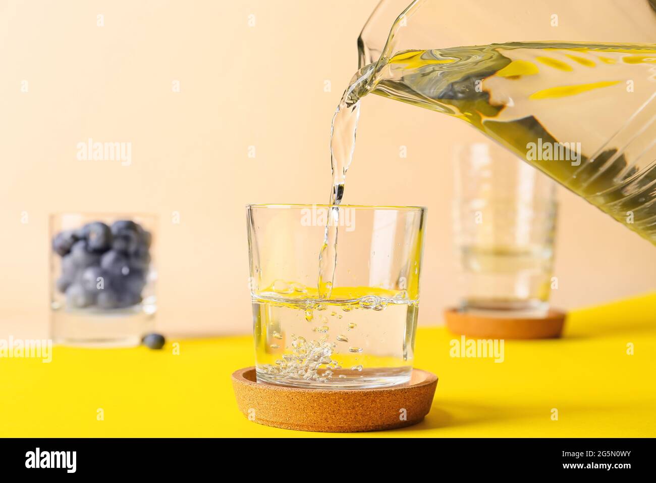 Pouring of water into glass on color background Stock Photo - Alamy