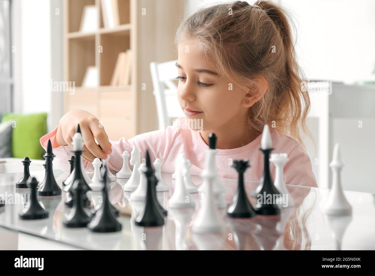 Cute little girl playing chess at home Stock Photo - Alamy