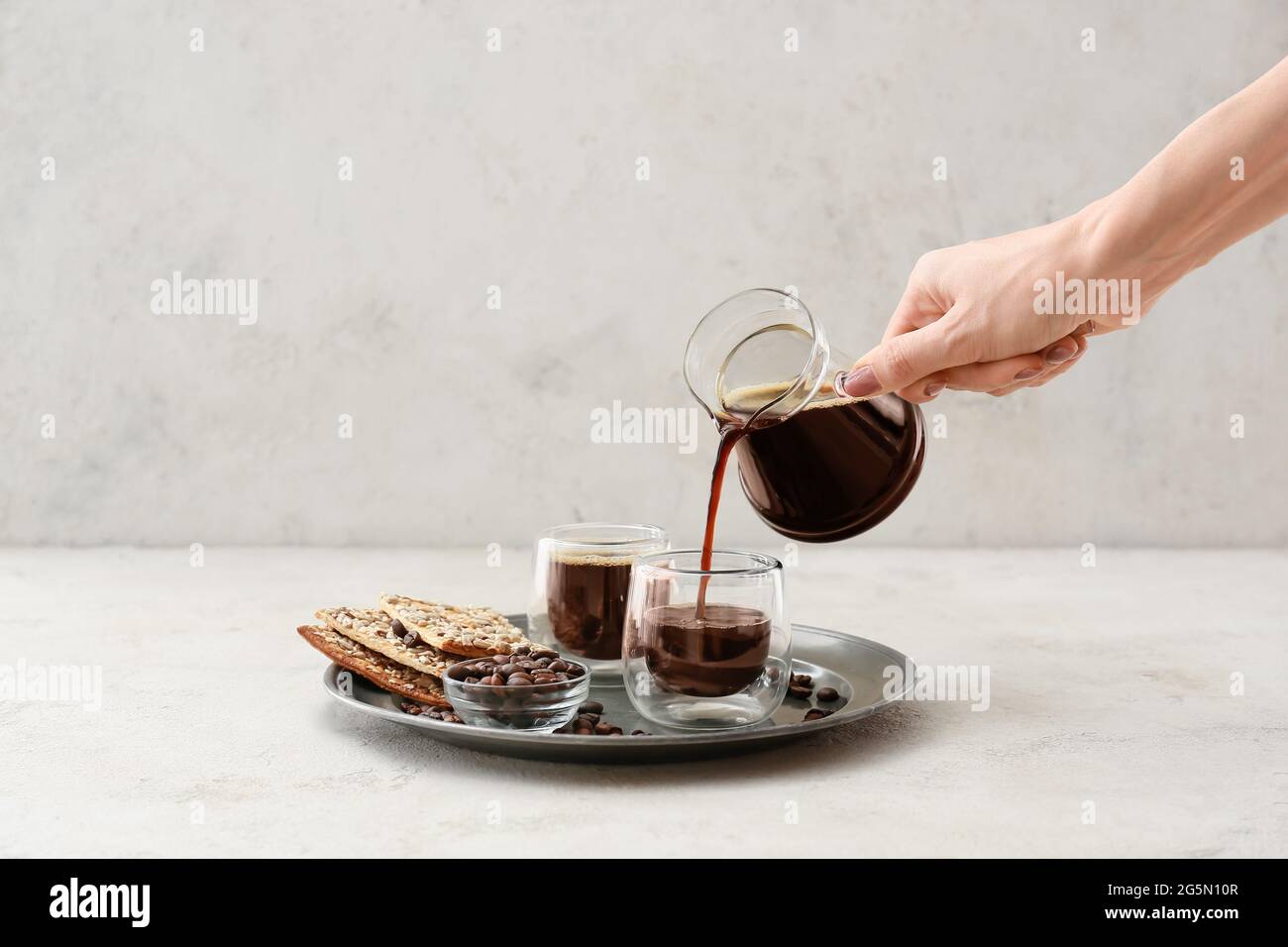 Woman pouring coffee from pot into cup on light background Stock Photo ...
