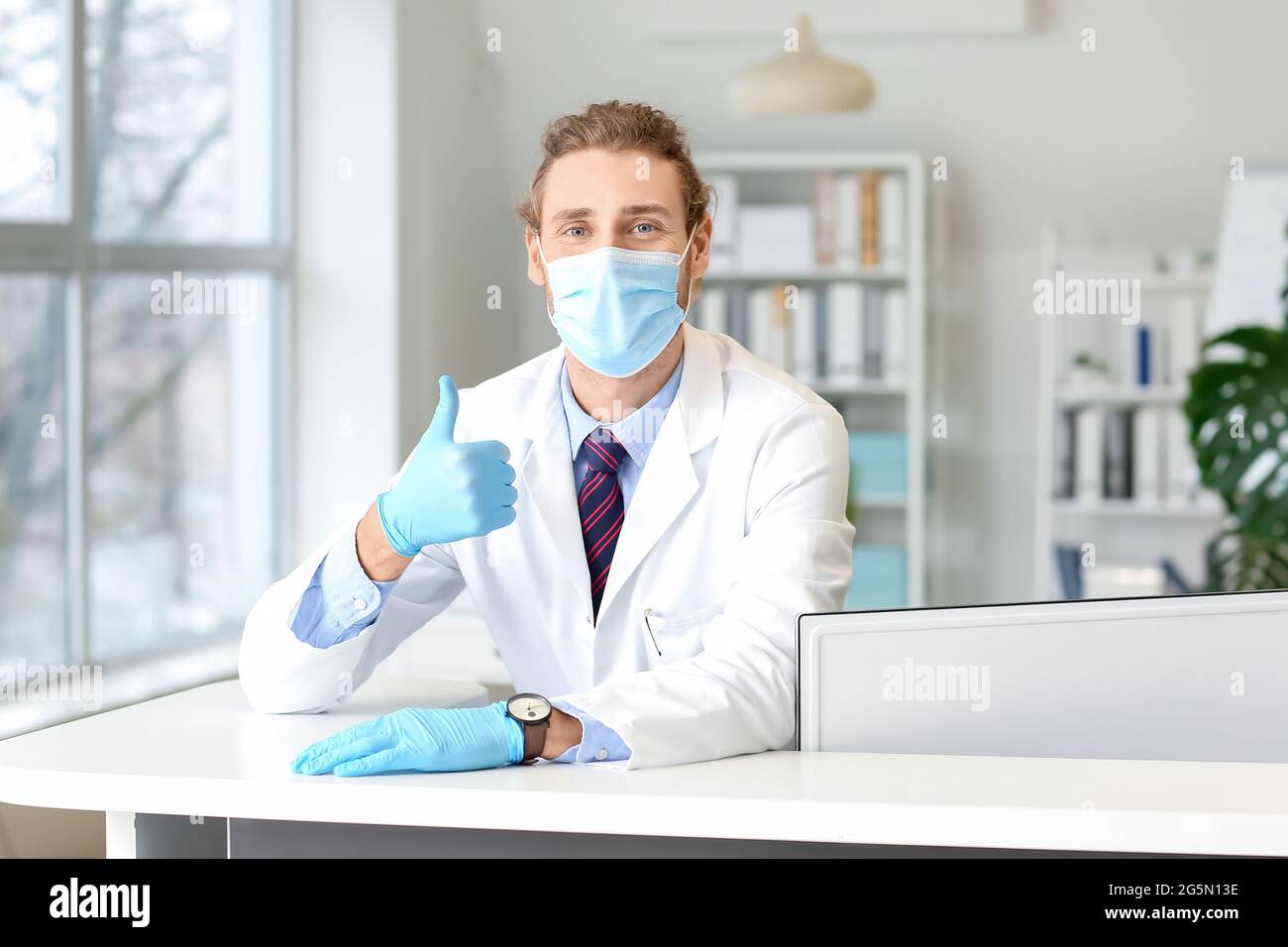 Male medical assistant showing thumb-up in clinic Stock Photo - Alamy