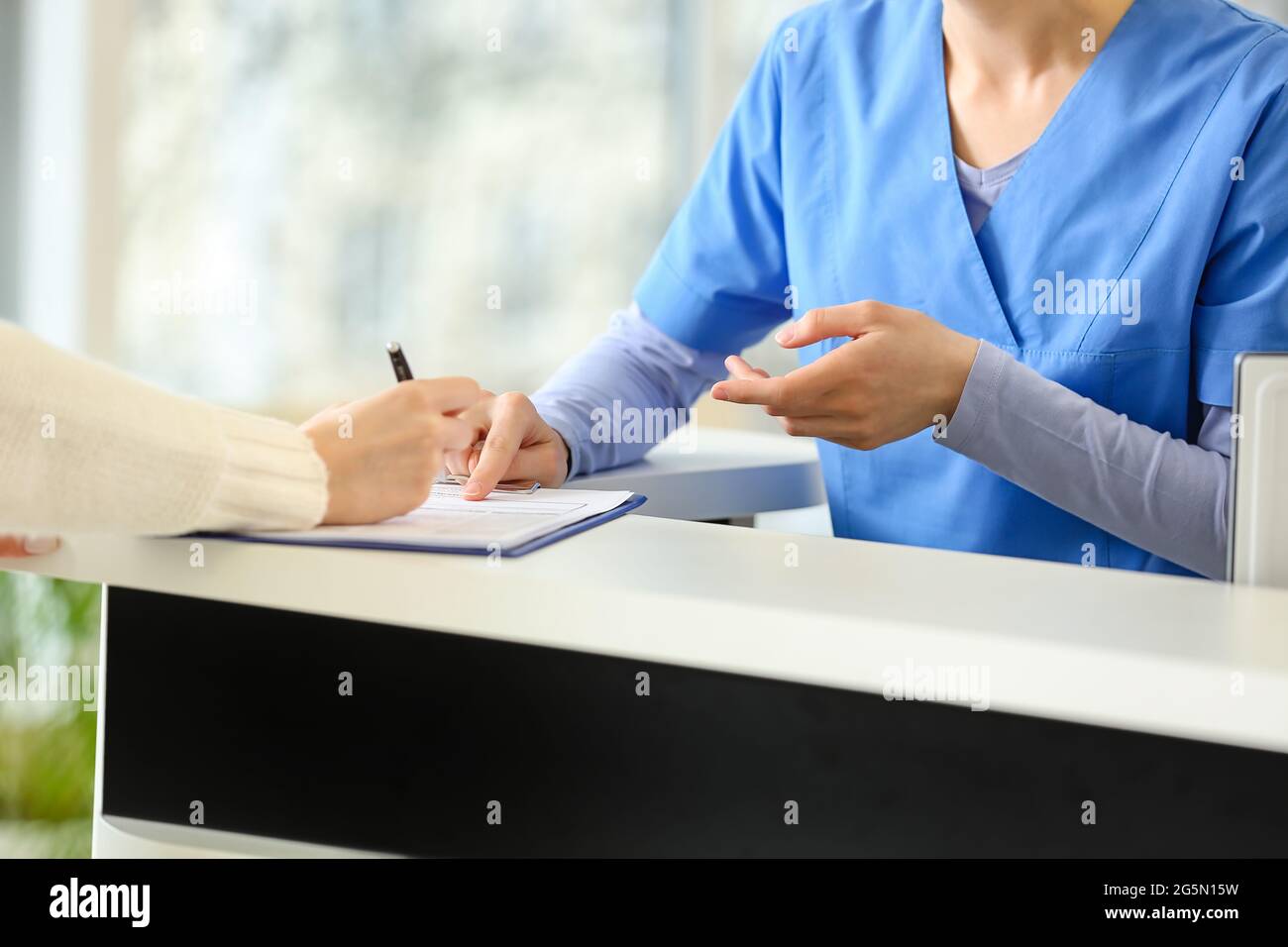 Female receptionist working with patient in clinic Stock Photo - Alamy