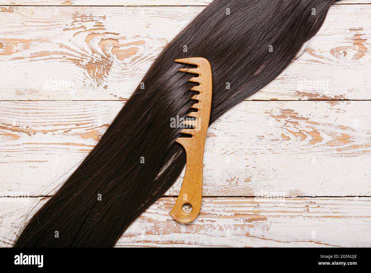 Hair strand and comb on light wooden background Stock Photo - Alamy