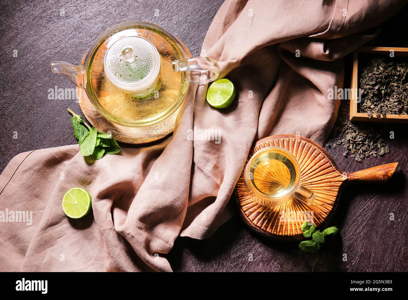 Wooden board with cup of tasty green tea and pot dark table Stock Photo ...