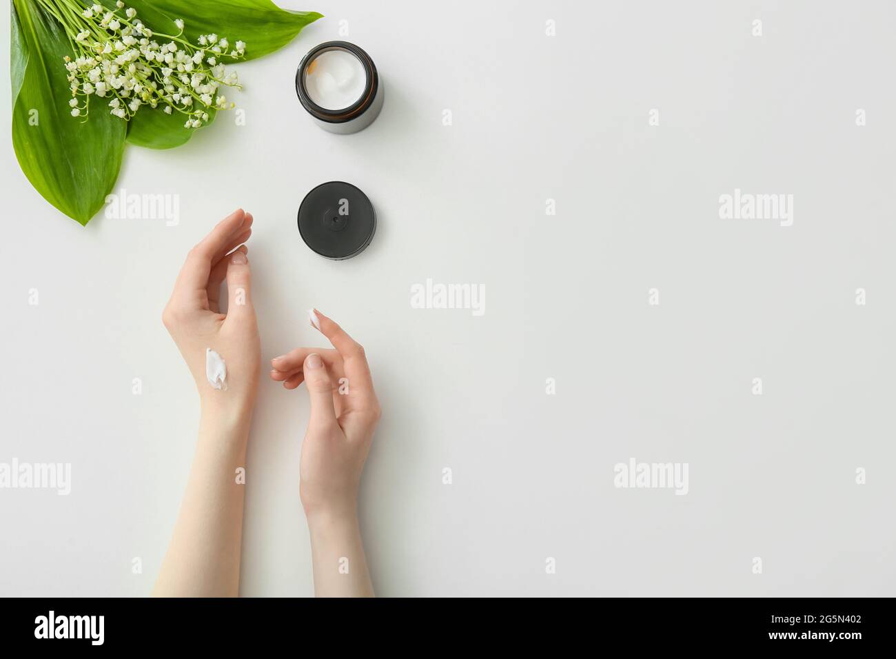 Woman applying hand cream on light background Stock Photo - Alamy