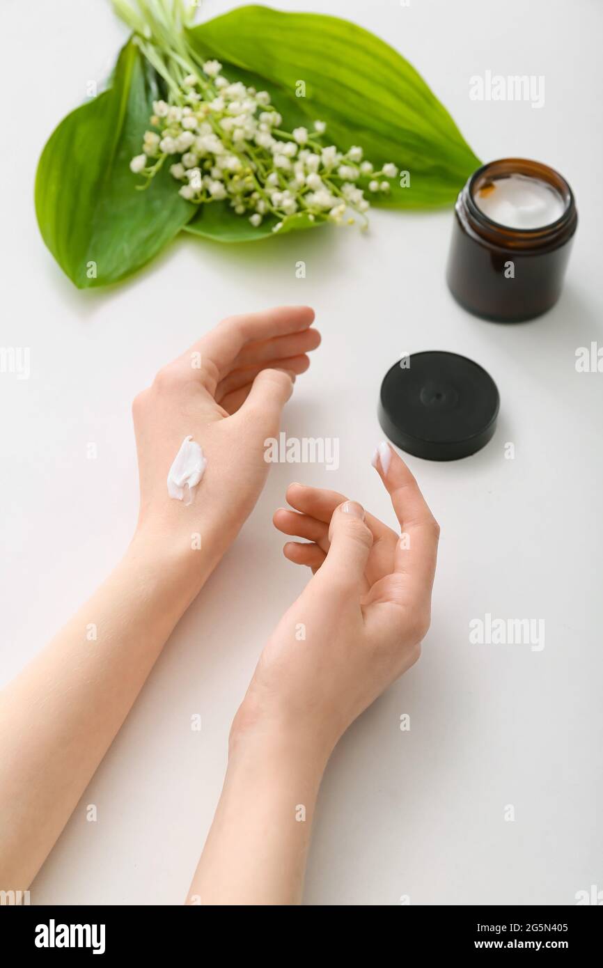 Woman applying hand cream on light background Stock Photo - Alamy