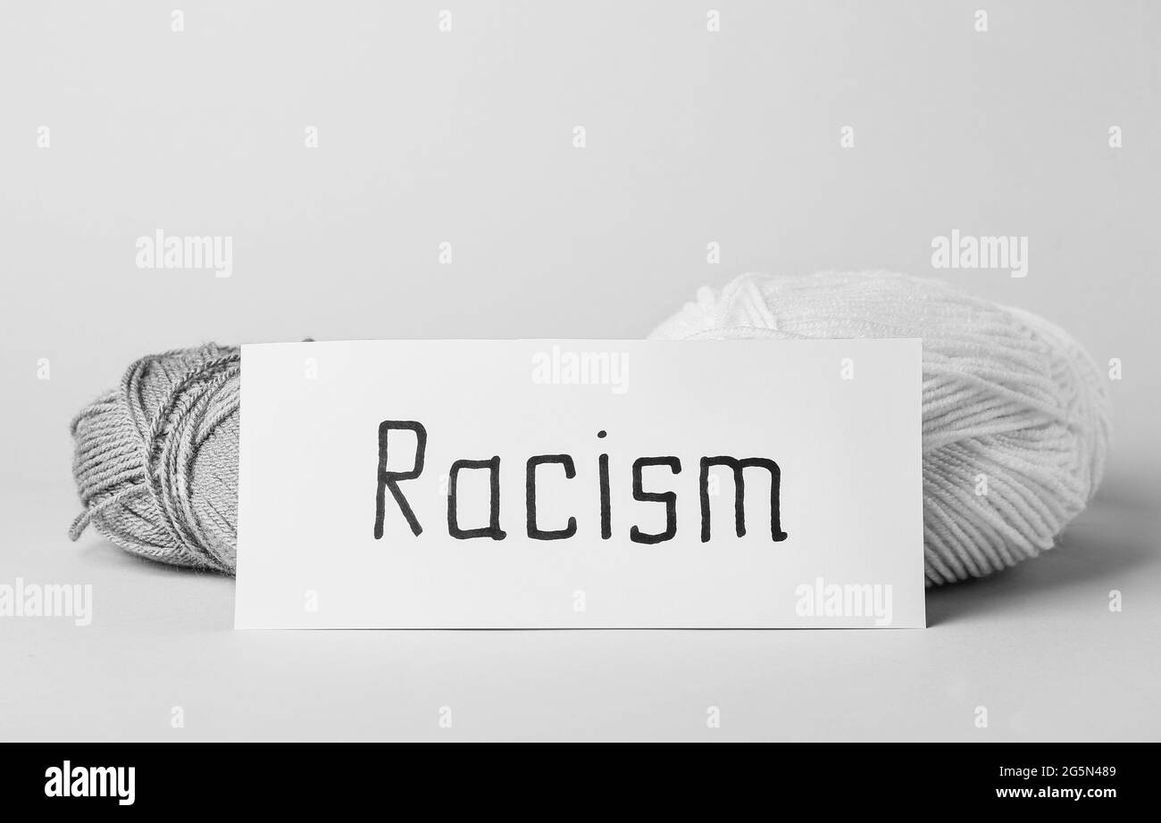 Paper piece with word RACISM and knitting yarn on white background ...