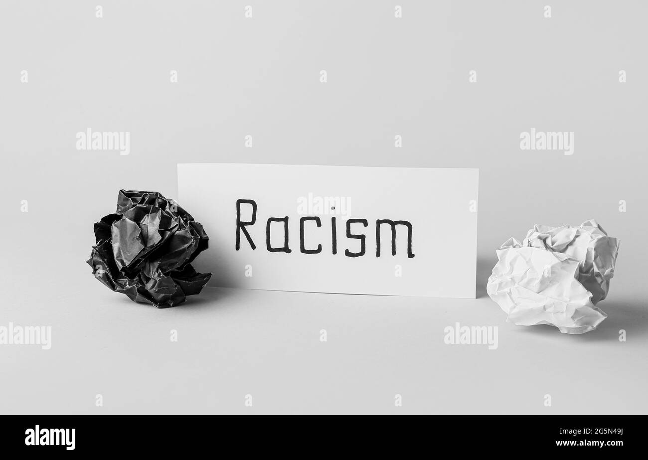 Paper piece with word RACISM and crumpled papers on white background ...