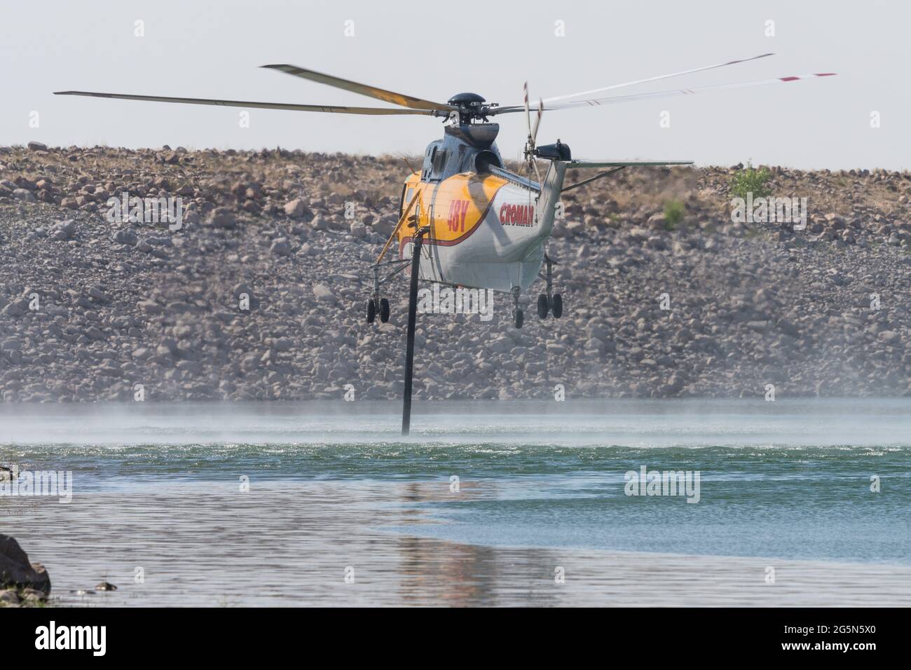 A Sikorsky S-61 fire-fighting helicopter fills with water from a lake ...