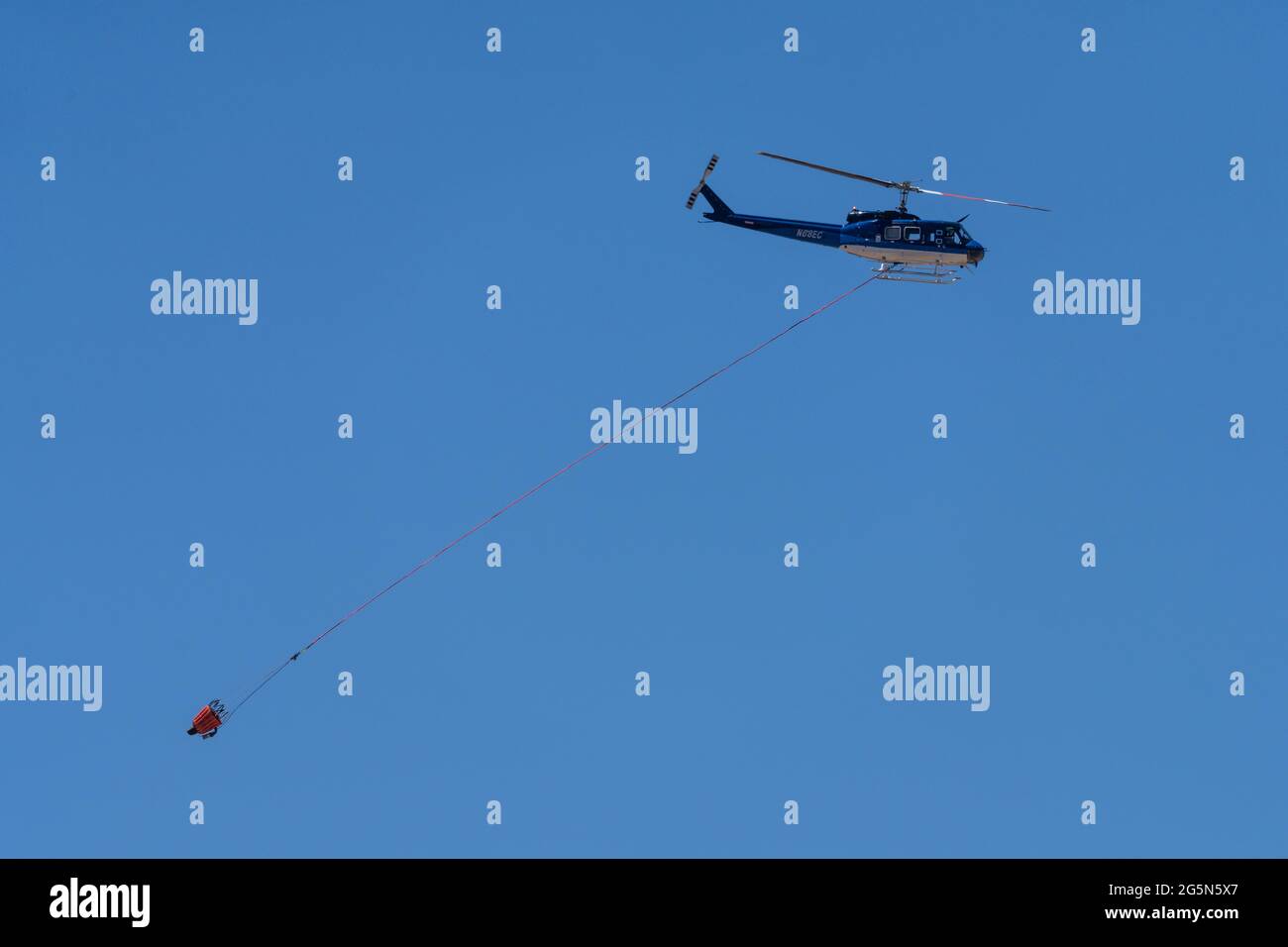 A Bell 205-A1 fire fighting helicopter carrying a helibucket to drop ...