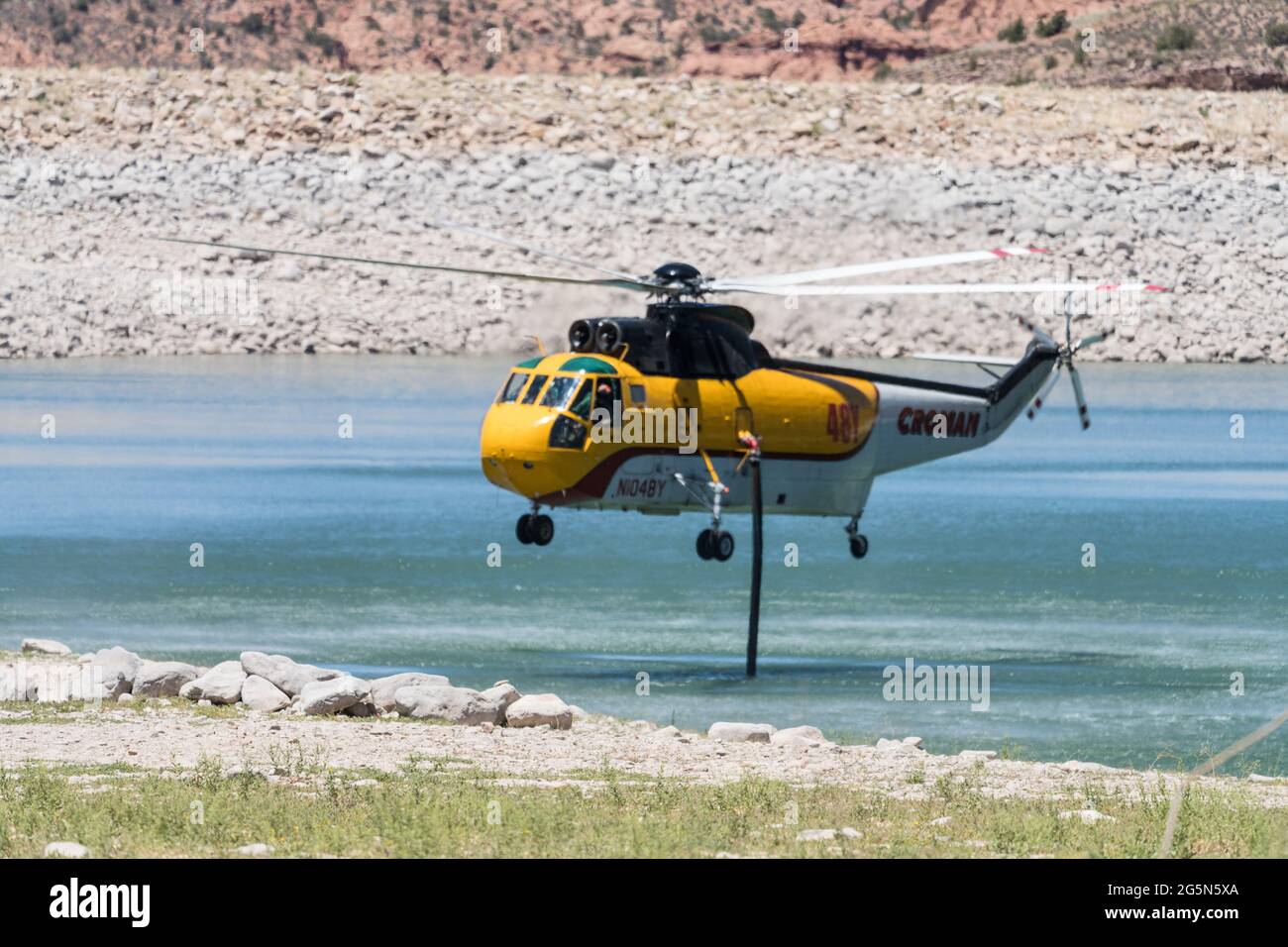 A Sikorsky S-61 fire-fighting helicopter fills with water from a lake ...