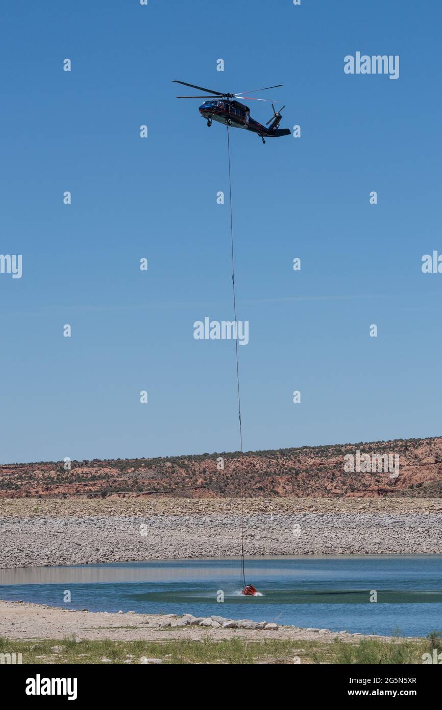 A Sikorsky UH-60 Blackhawk fire-fighting helicopter lowers a helibucket ...