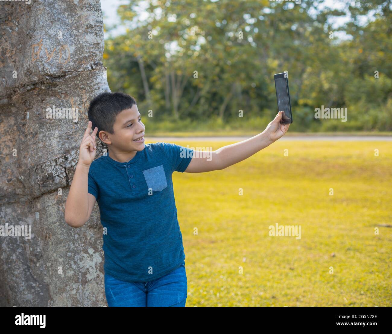 boy taking a selfie next to a tree Stock Photo - Alamy