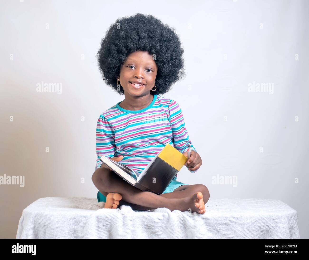 African girl child with an afro hair style shows her love for education ...