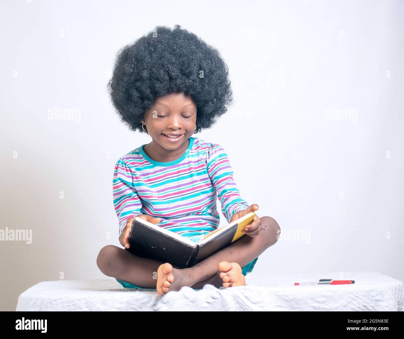 African girl child with an afro hair style shows her love for education ...